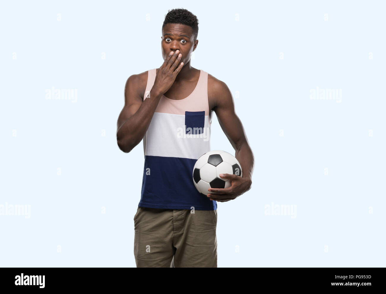 Young african american man holding soccer football ball cover mouth ...