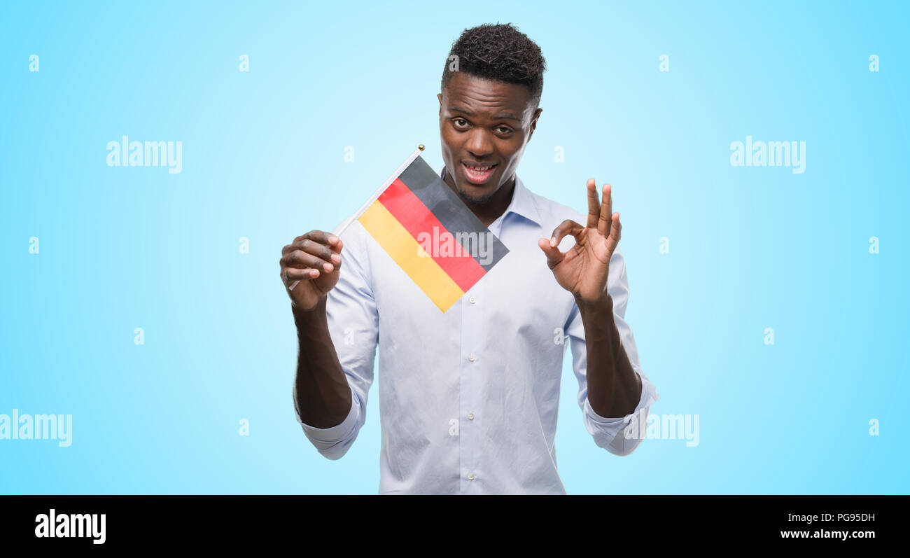 Young african american man holding german flag doing ok sign with ...