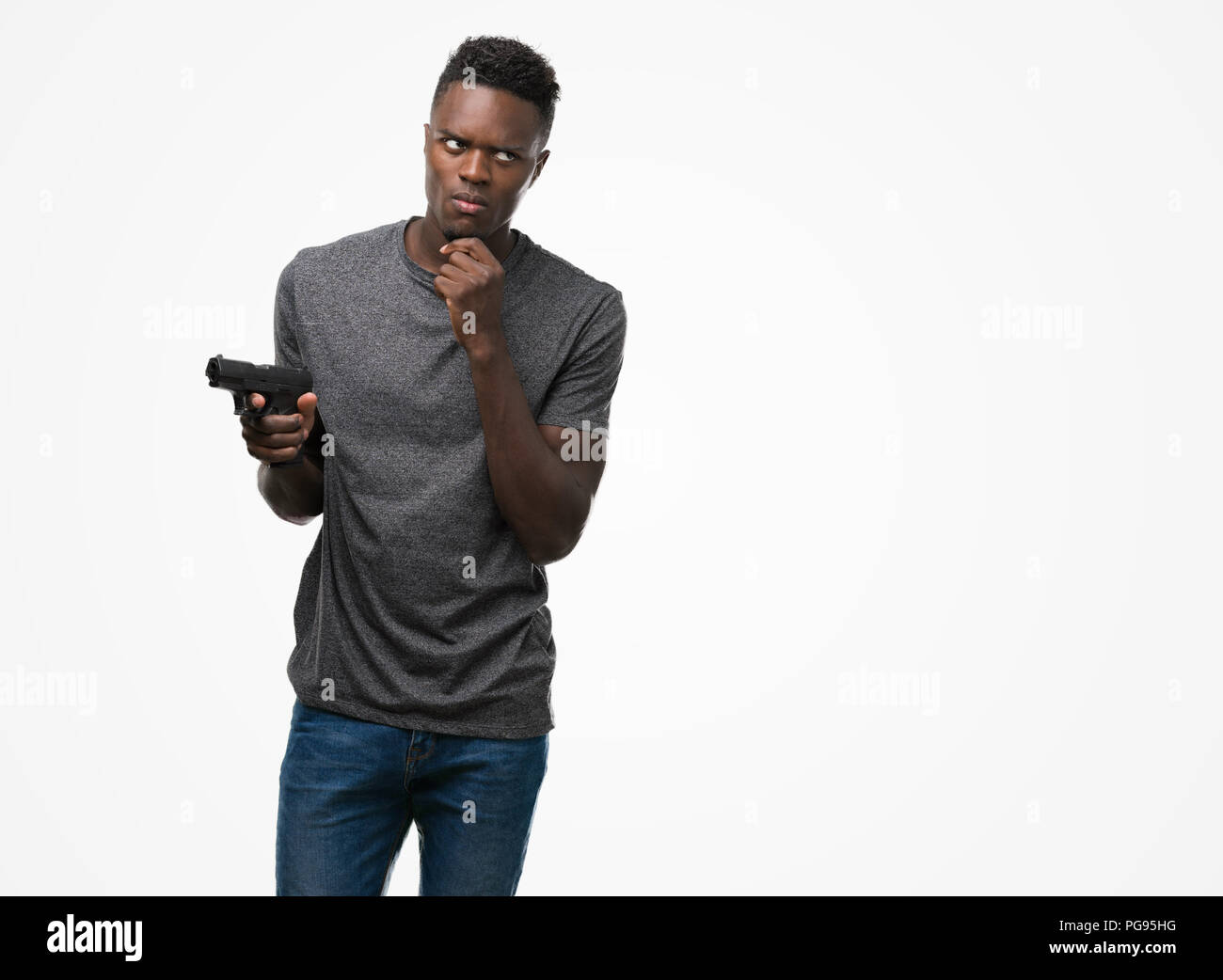 Young african american man holding a gun serious face thinking about ...