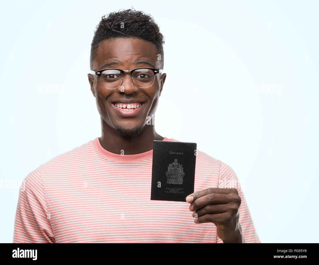 Young african american man holding canadian passport with a happy face ...
