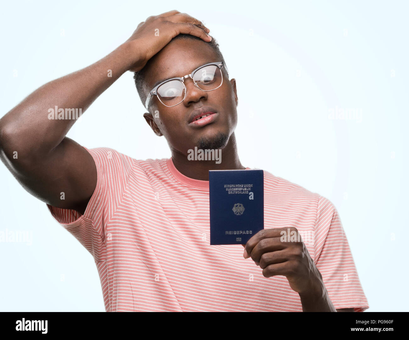 Young african american man holding german passport stressed with hand ...