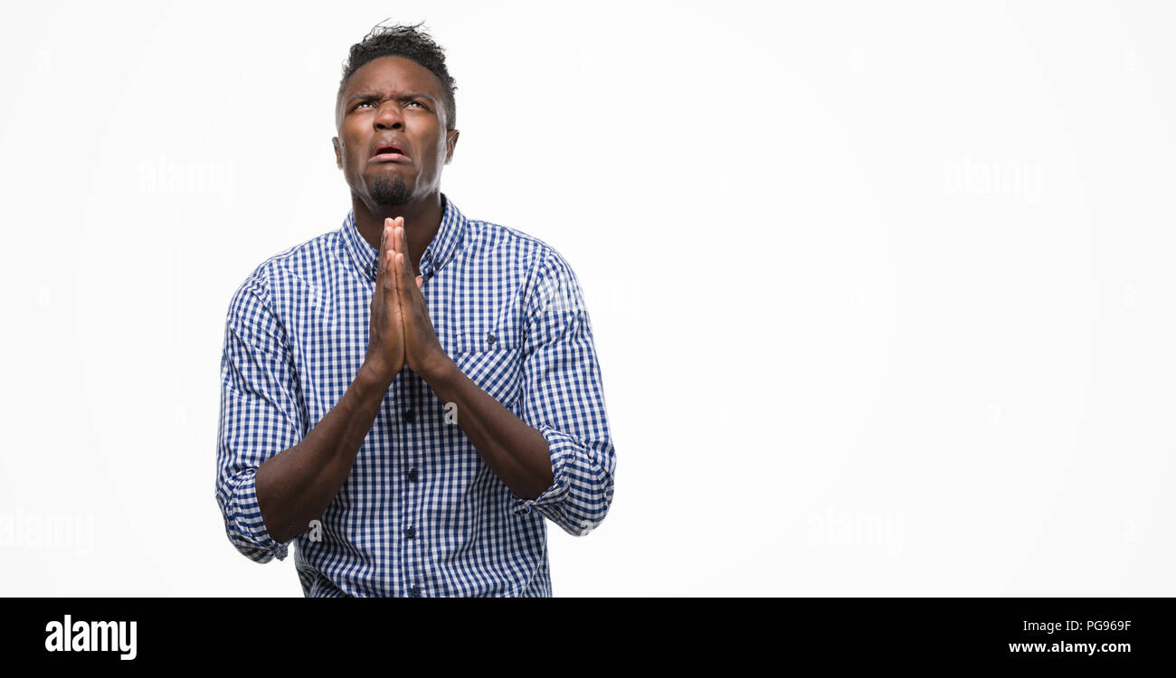 Young african american man wearing blue shirt begging and praying with ...