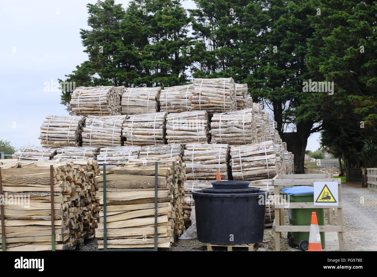 Bundles of metre length wooden logs neatly piled in UK garden centre ...