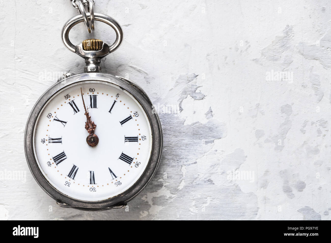 two minutes to twelve o'clock on vintage pocket watch on white concrete ...