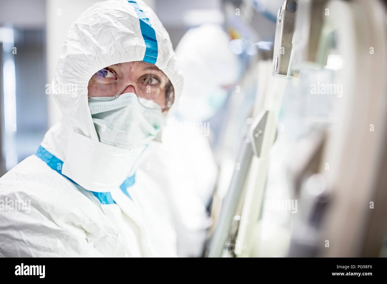 Lab technician wearing a protective suit, face mask and safety goggles ...