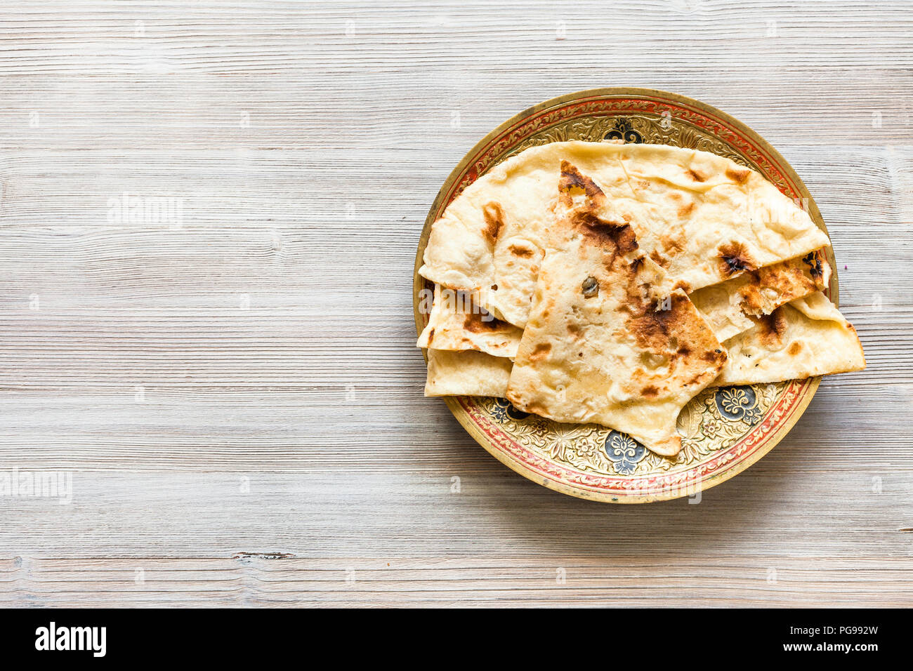 Indian cuisine - Naan flat bread baked in tandoor on brass plate on ...