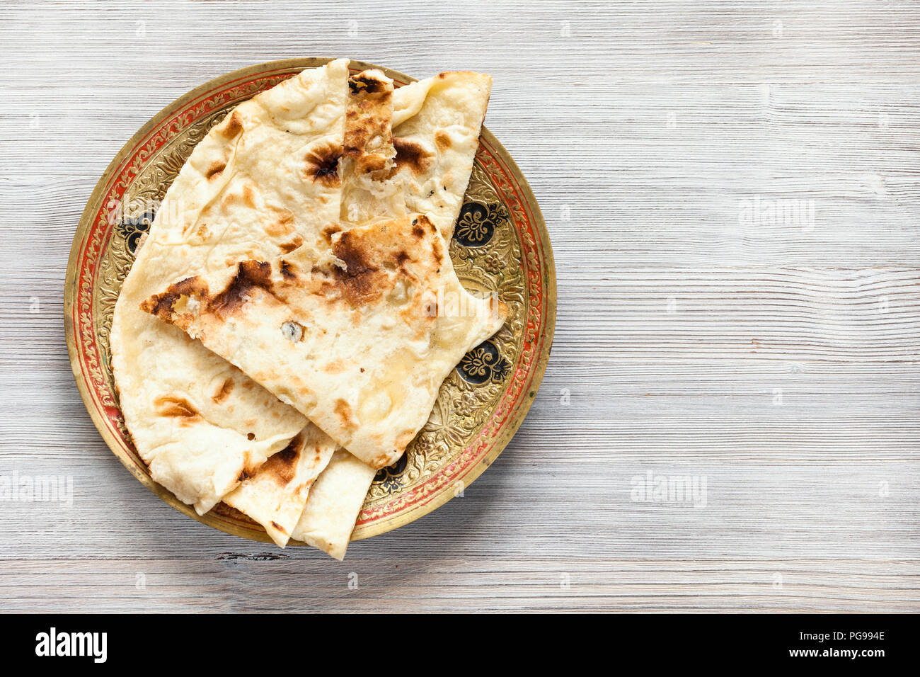 Indian cuisine - Naan flat bread baked in tandoor on brass plate on ...