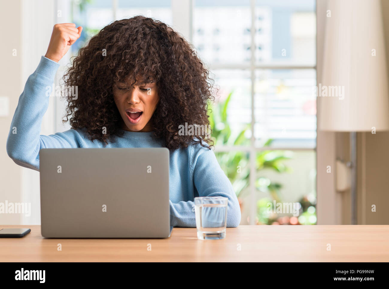 African american woman using laptop computer at home annoyed and ...