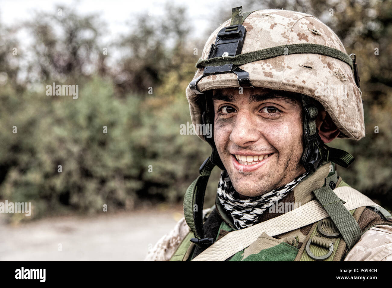 Shoulder portrait of happy smiling young soldier in battle helmet with ...