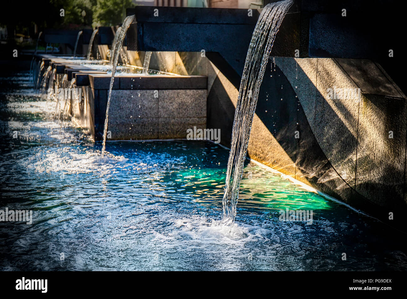 The morning sunrise light at a trickling set of fountains on a ...