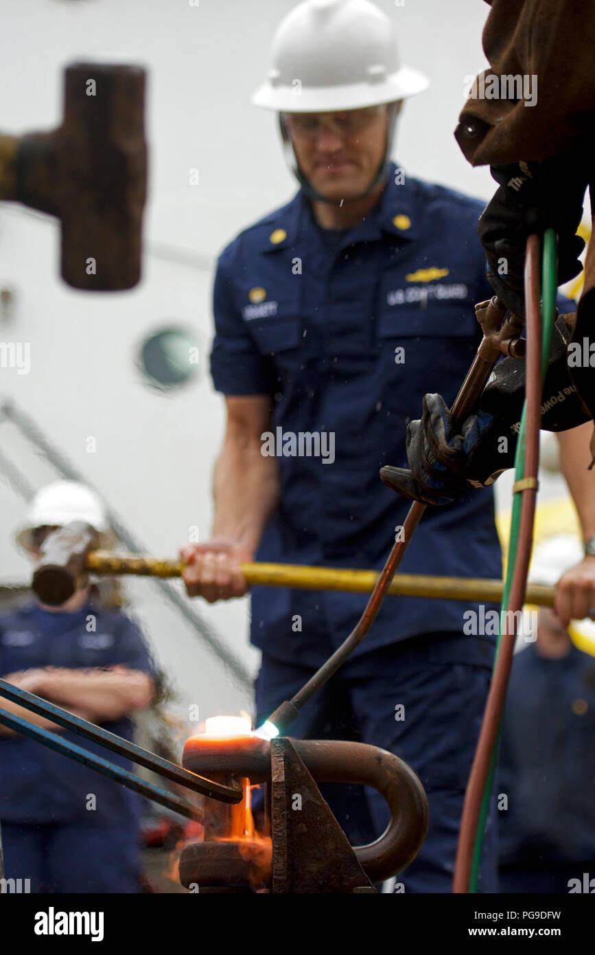 A Coast Guard lieutenant commander prepares for a shackle pin to be ...