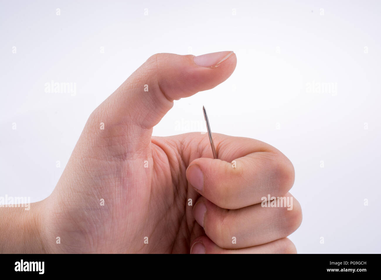 Hand holding a needle on a white background Stock Photo - Alamy