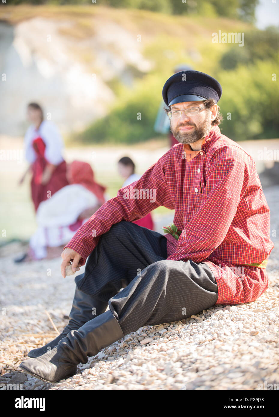 A man in a Russian folk costume sitting on a background of beautiful ...
