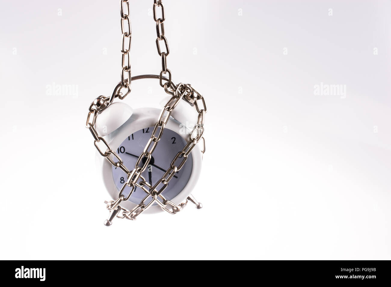 White color alarm clock in chain on a white background Stock Photo - Alamy
