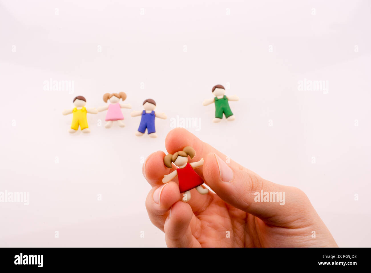 Hand holding colorful dressed children figure on a white background ...