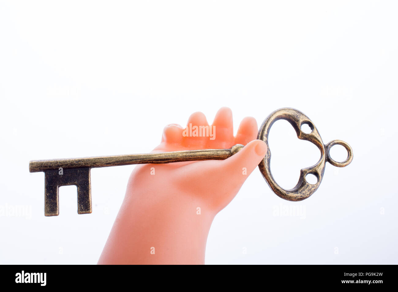 Doll holding a key on a white background Stock Photo - Alamy