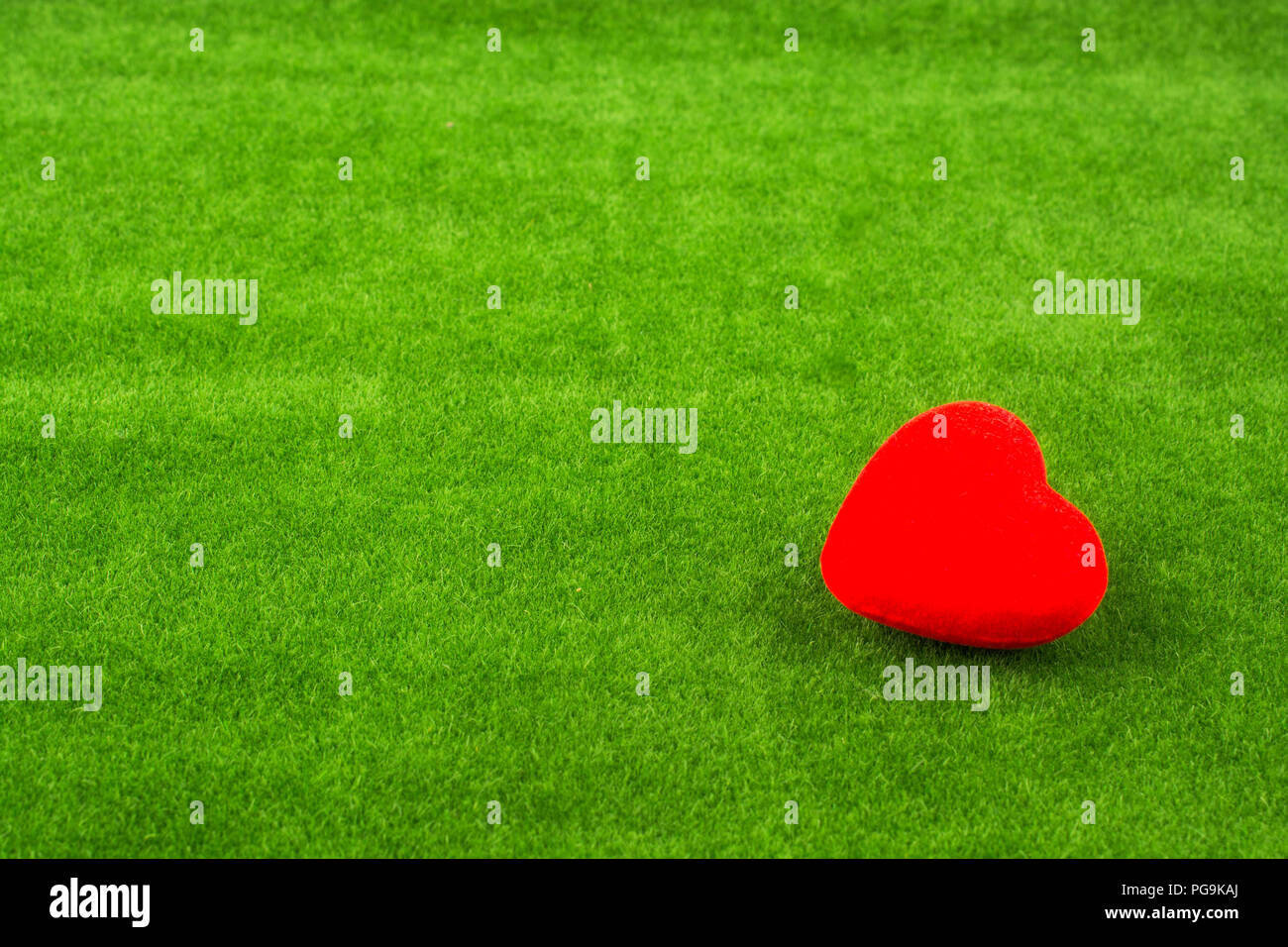The red heart shape object placed on green grass Stock Photo - Alamy