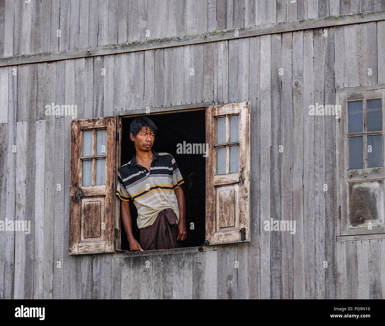 Inle, Myanmar - Feb 15, 2016. A man standing at thư window of wooden ...