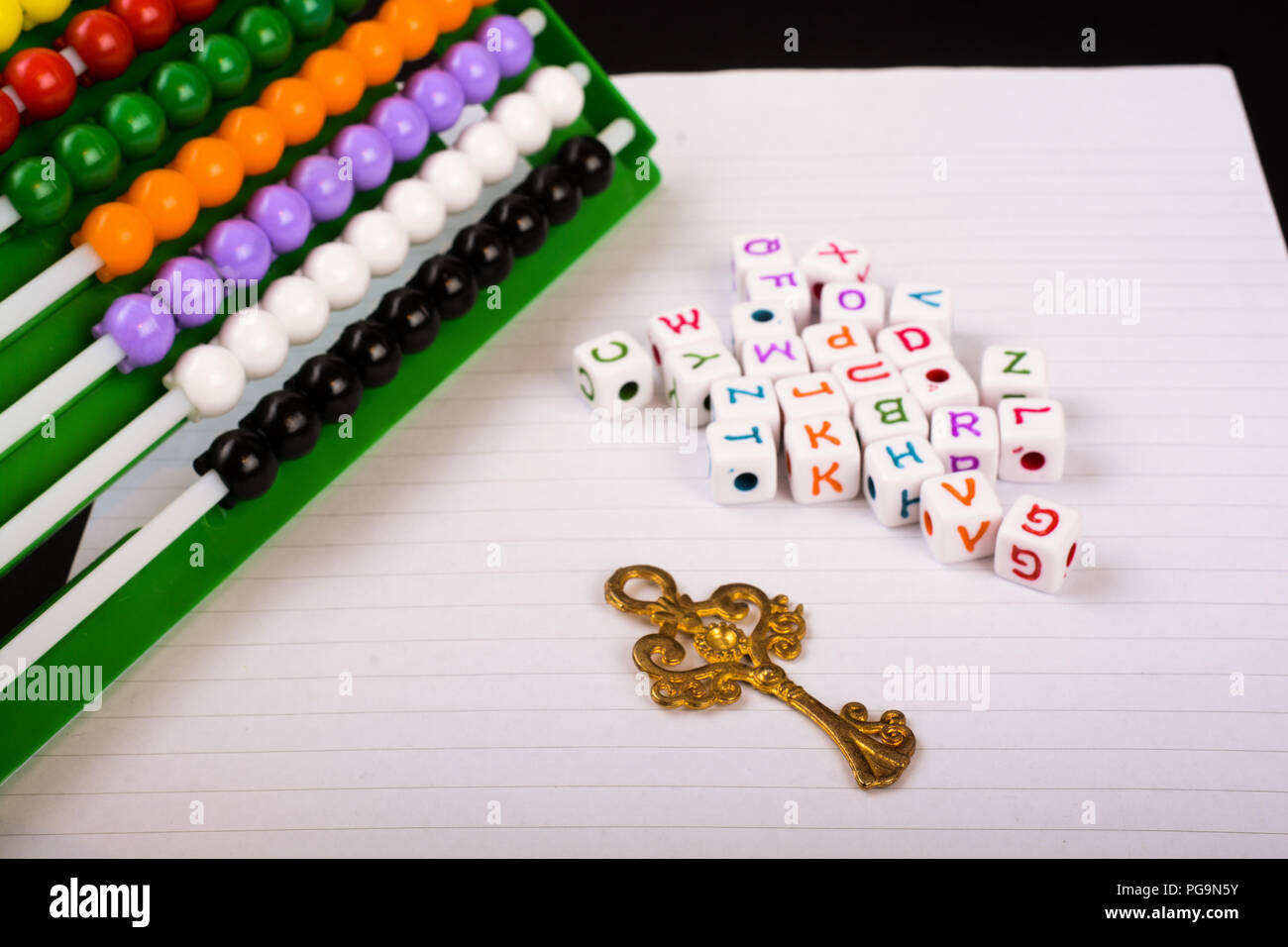Abacus, key and cube letters of alphabet side by side on white paper ...