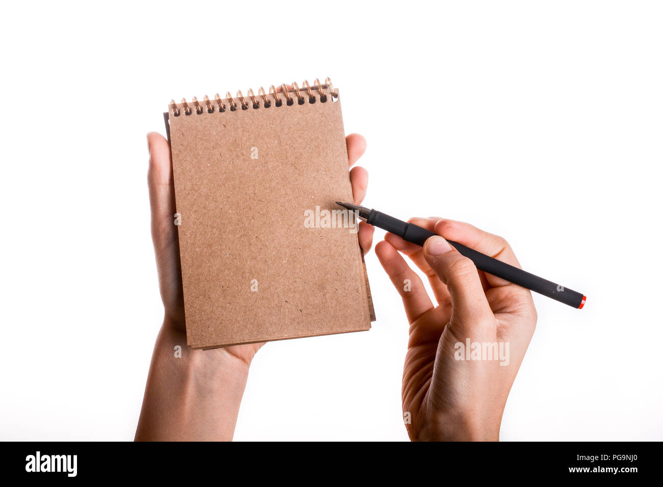 Spiral brown notebook with a pen held by a child on a white background ...