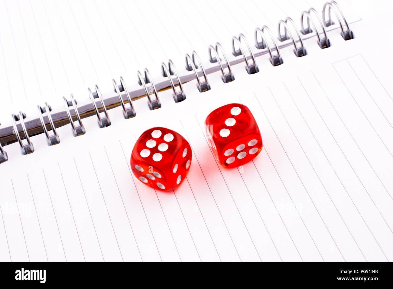 Red dice on a a notebook on a white background Stock Photo - Alamy