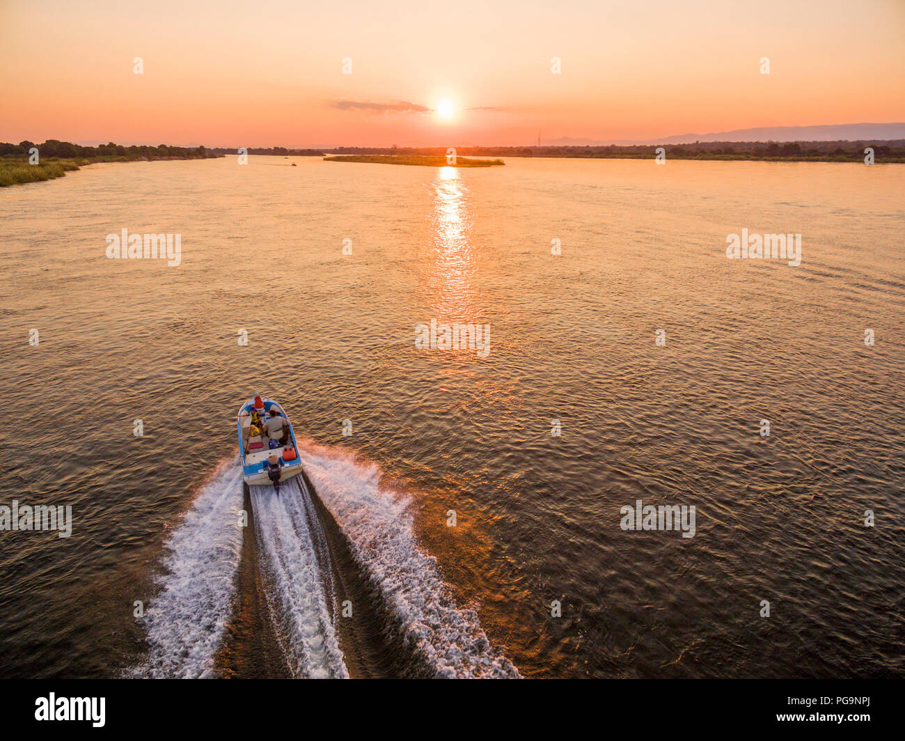 A speedboat seen heading into a sunset on the Zambezi River, Zimbabwe ...