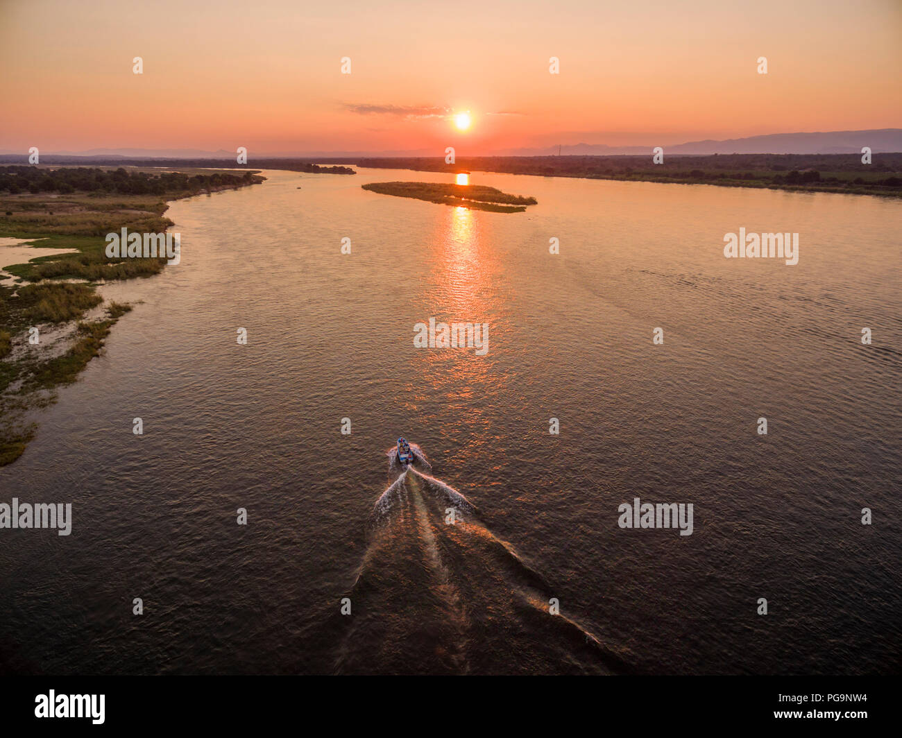 A speedboat seen heading into a sunset on the Zambezi River, Zimbabwe ...