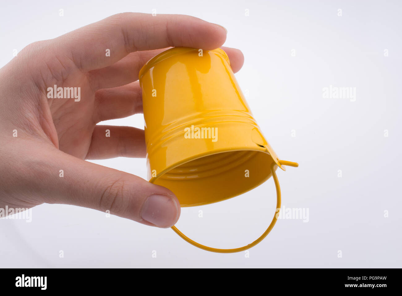 Hand holding a yellow bucket on a white background Stock Photo - Alamy