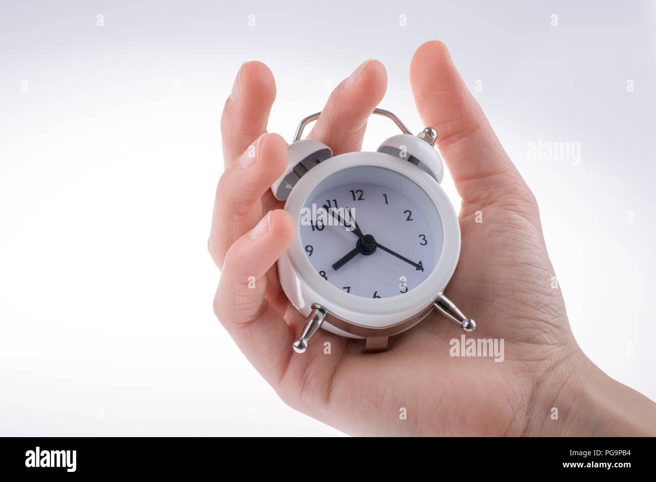 Alarm clock in hand on a white background Stock Photo - Alamy