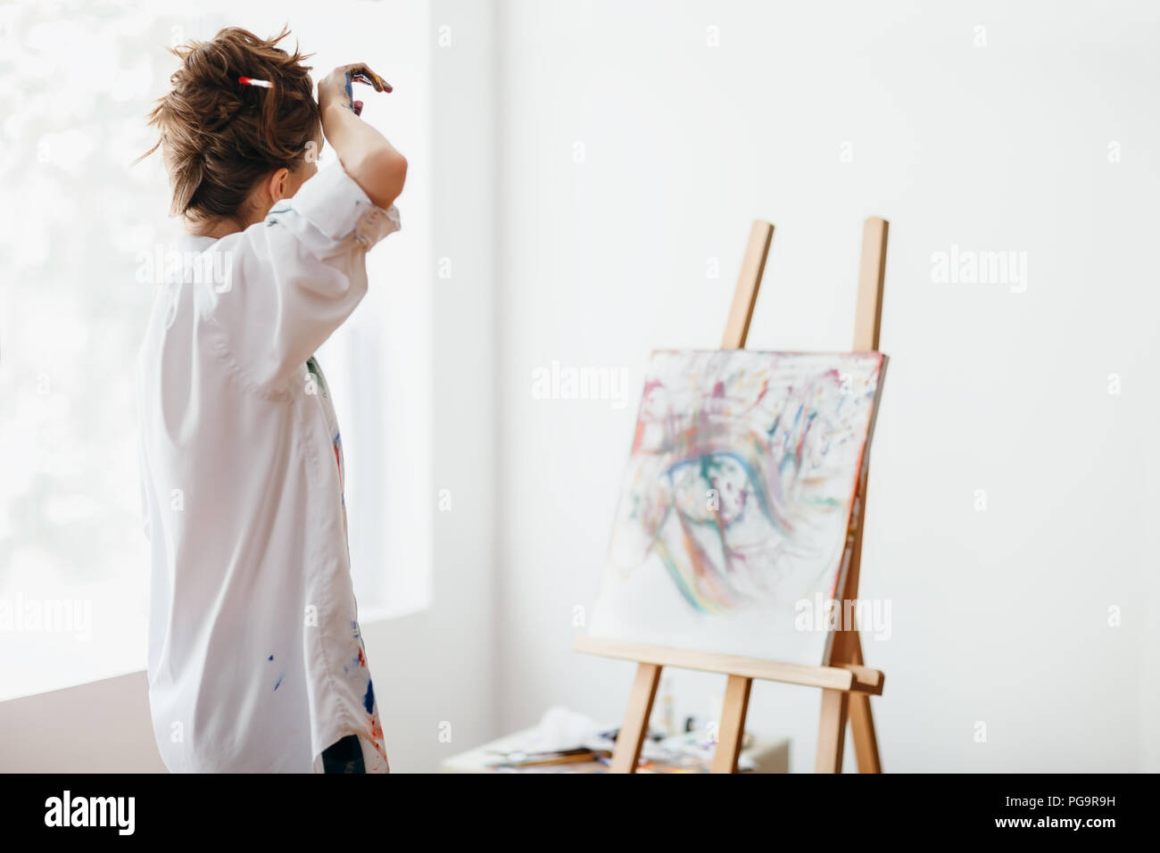 Artist tired after drawing, wipes forehead, rear view. Woman in ...