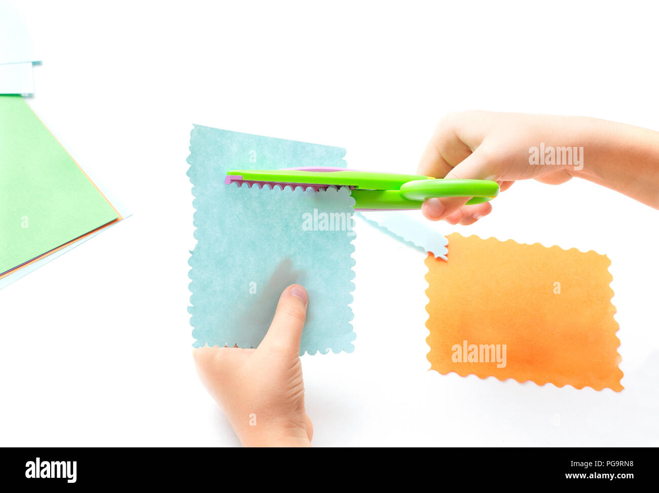 Children's hands cut out colored paper with figured scissors ...