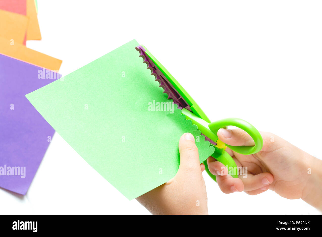 Children's hands cut out colored paper with figured scissors ...