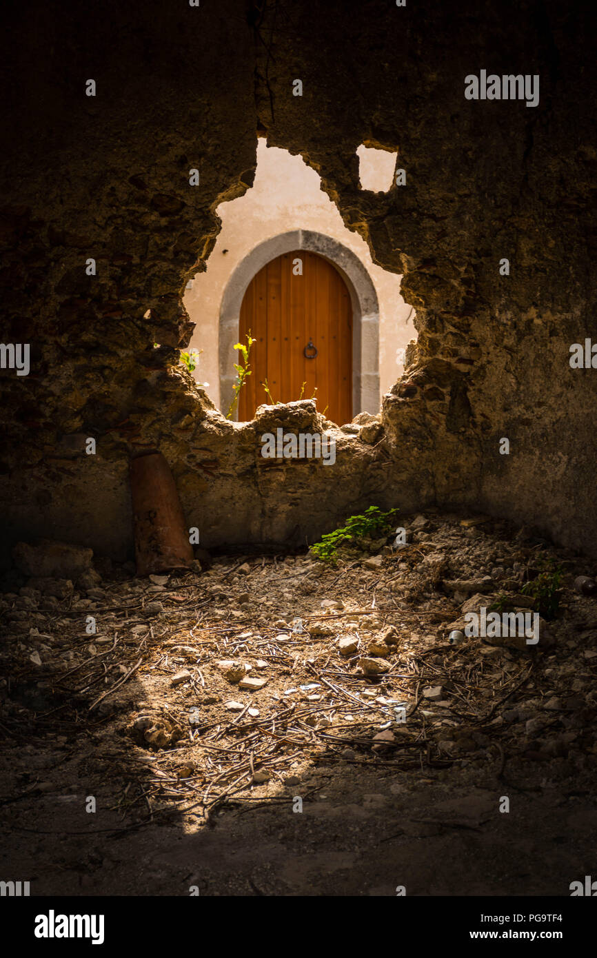 An old wooden arched door in Sicily seen through a broken hole in a ...