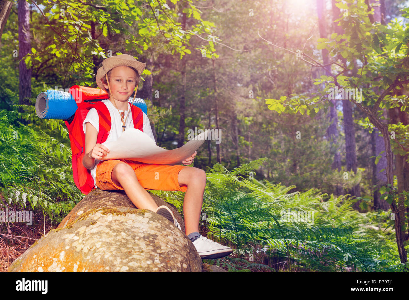 Boy with map sit on stone during hike Stock Photo - Alamy