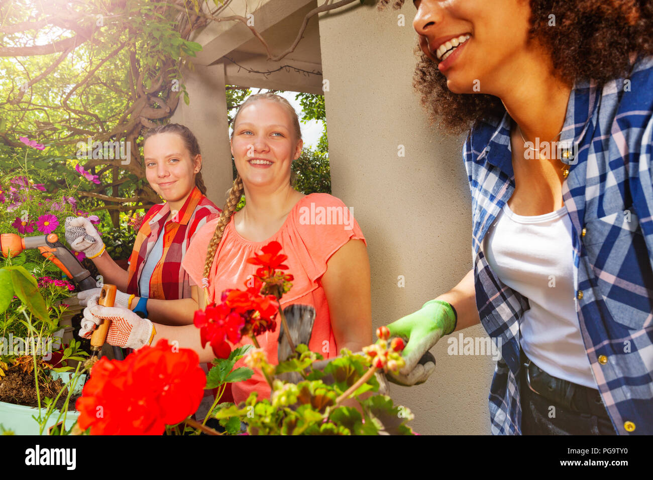 Happy girls planting flowers on terrace in summer Stock Photo - Alamy