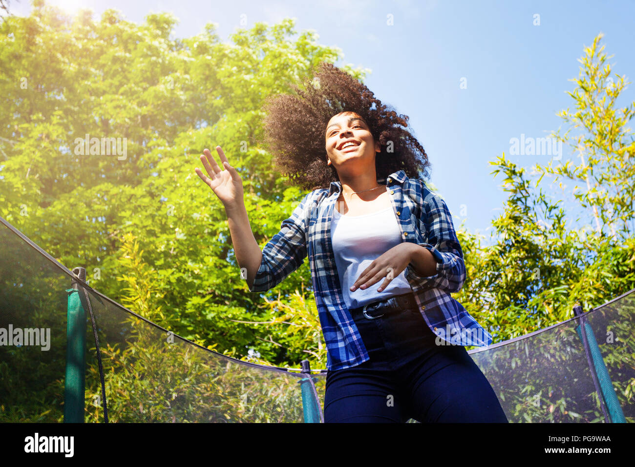 Joyful African girl teenager jumping on trampoline Stock Photo - Alamy
