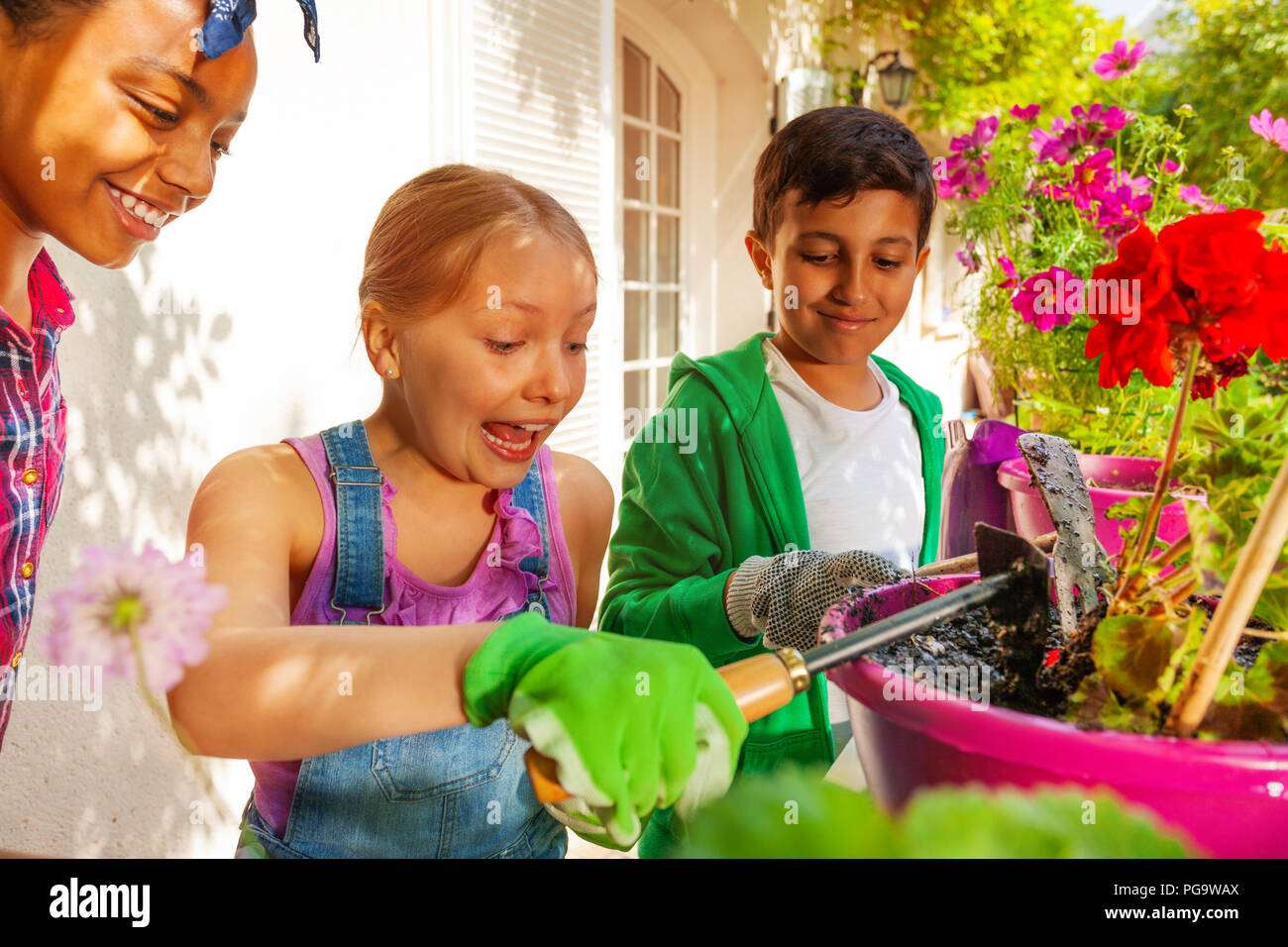 Three happy friends taking care of flower plants Stock Photo - Alamy