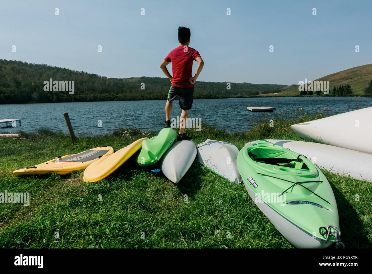 a teenager posing on top of filed boat facing the lake Stock Photo - Alamy