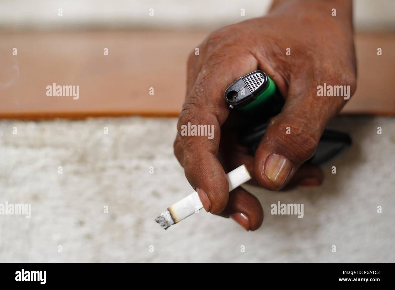 Photo of a hand with wrinkled skin holding a cigarette and a lighter ...