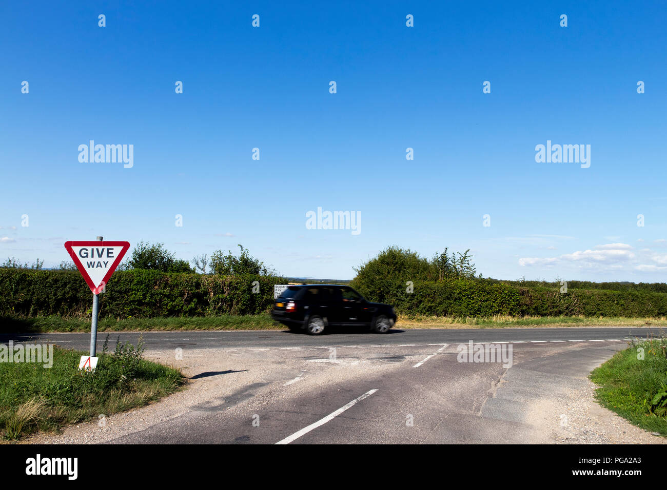 give way road sign on country lane joining main highway junction in ...