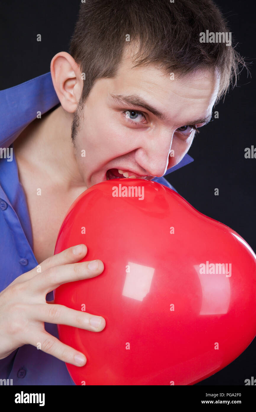 Young guy holding a red heart-shaped balloon Stock Photo - Alamy