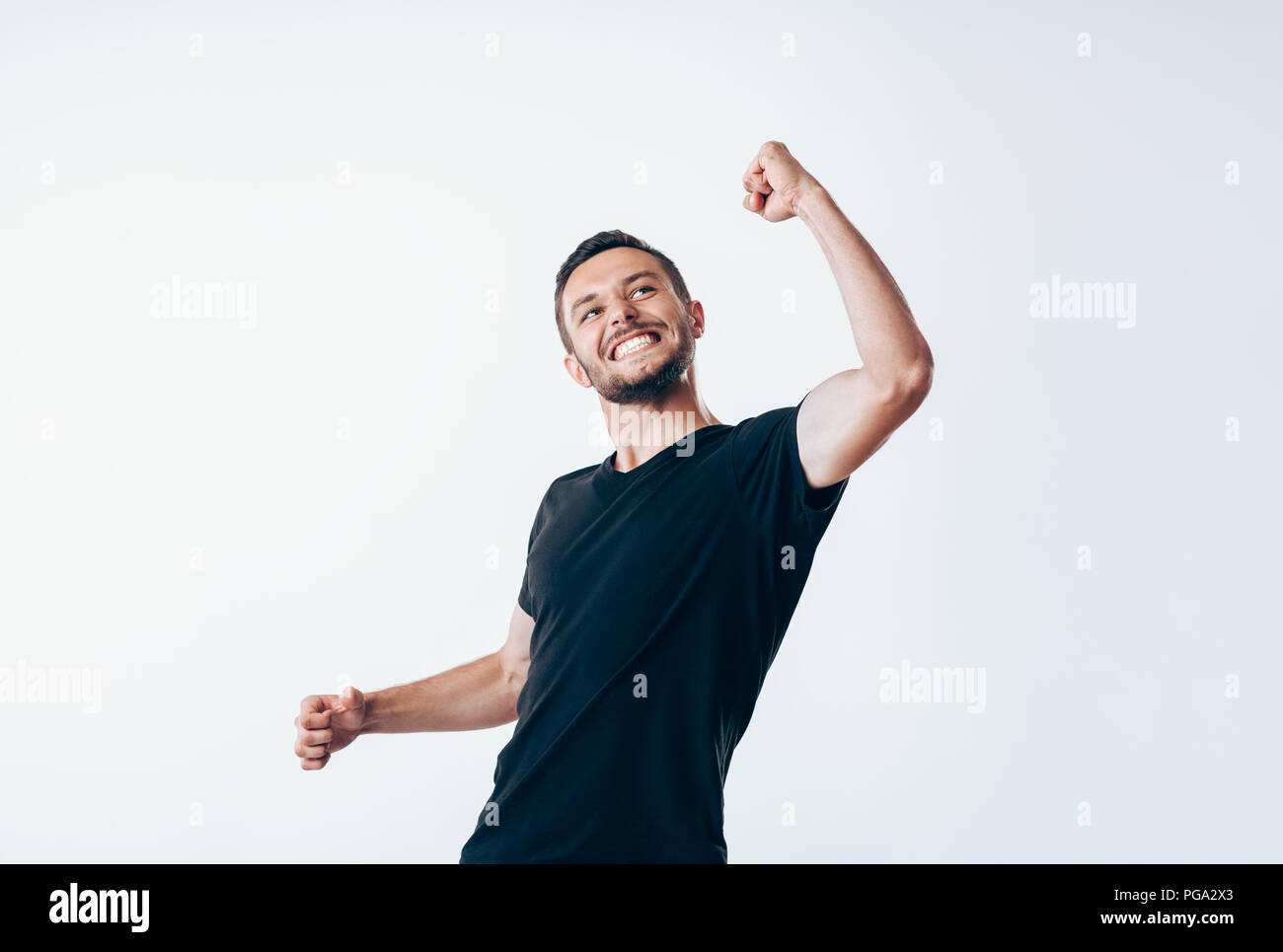 Handsome young man with arms up celebrating success Stock Photo - Alamy