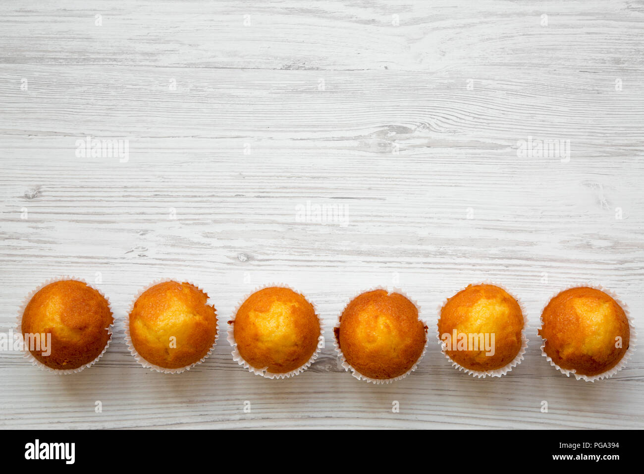 Fresh muffins on a white wooden background, view from above. Copy space ...