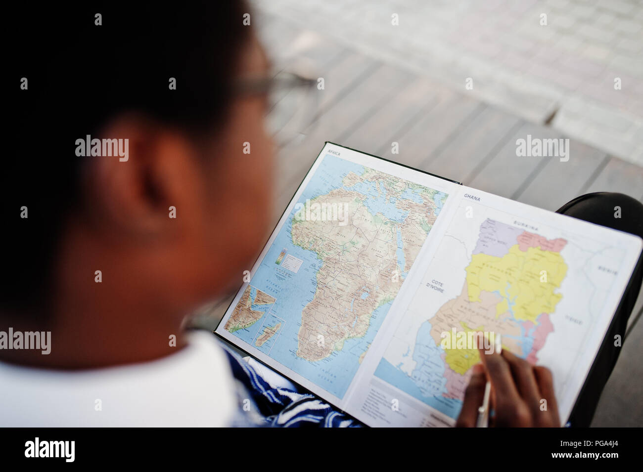 African man in traditional clothes and glasses looking on map of Africa ...