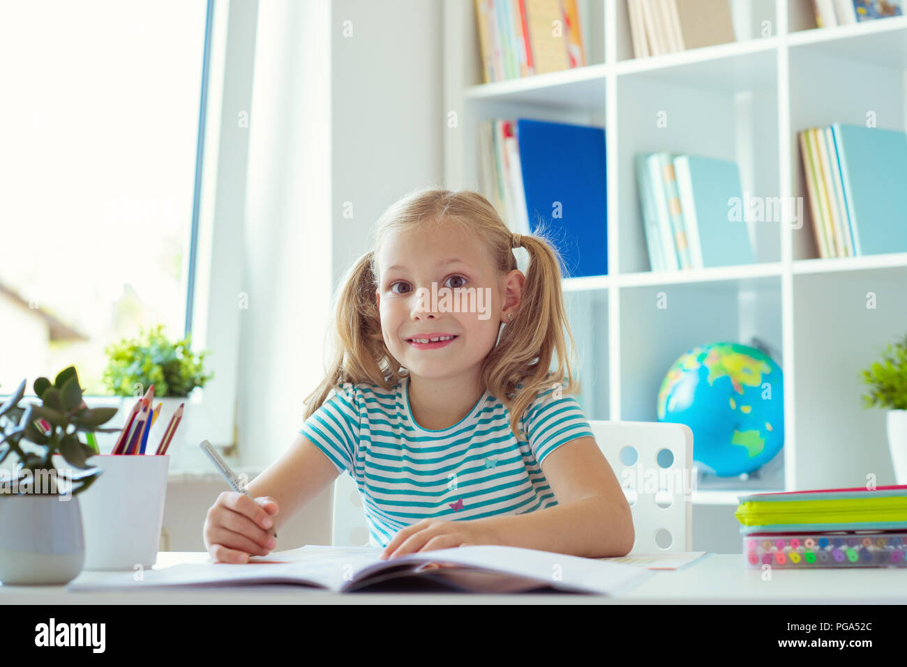 Portrait of pretty schoolgirl at classroom writing at the table Stock ...