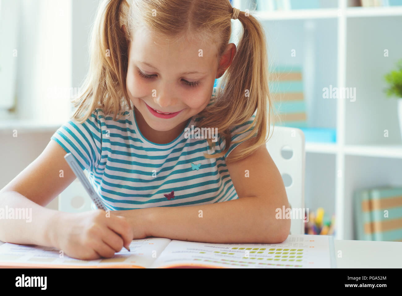 Portrait of pretty schoolgirl at classroom writing at the table Stock ...