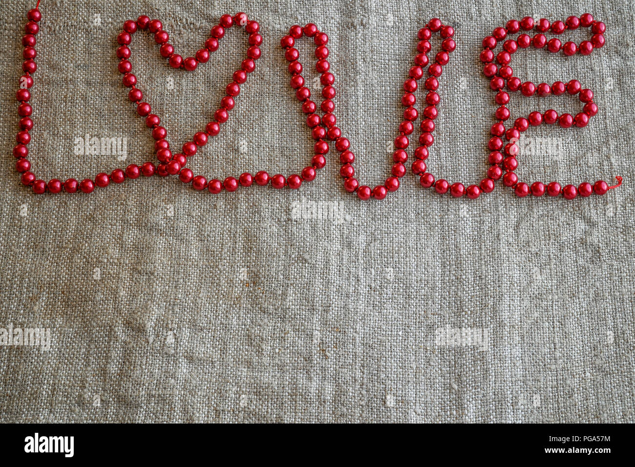 Created LOVE with red feathers on old fabric Stock Photo - Alamy