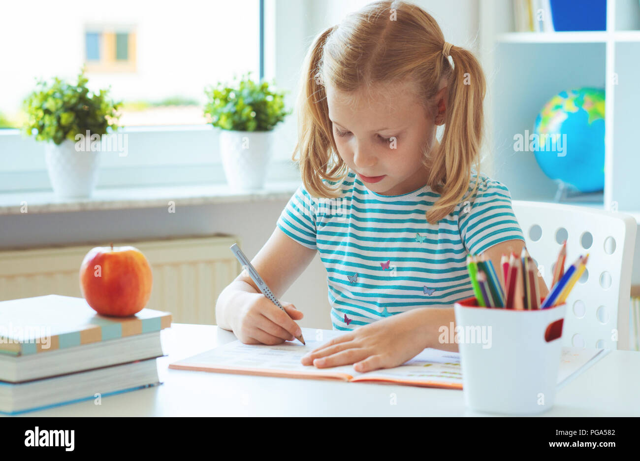 Portrait of pretty schoolgirl at classroom writing at the table Stock ...