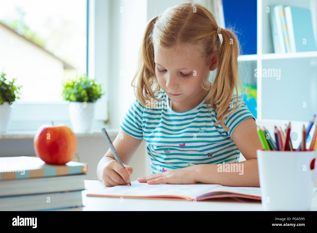Portrait of pretty schoolgirl at classroom writing at the table Stock ...