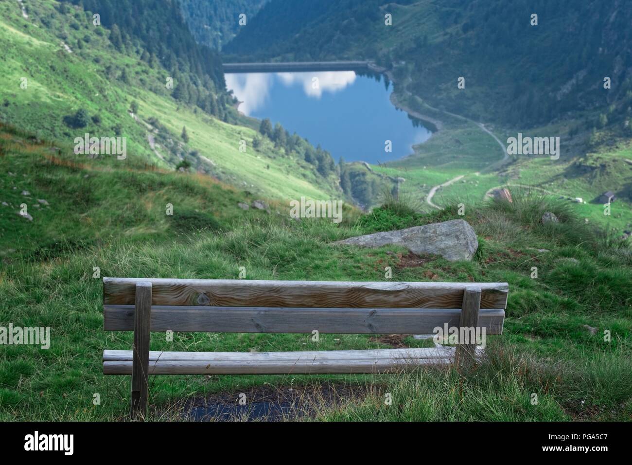 Isolated bench facing a valley in the Italian Alps with no people. A ...